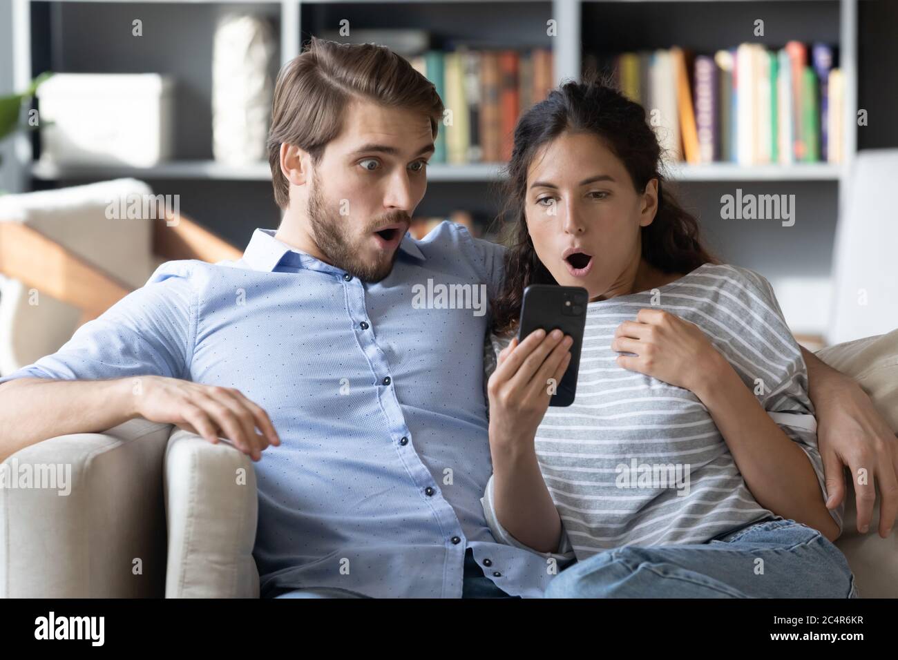 Shocked young man and woman looking at phone screen Stock Photo - Alamy