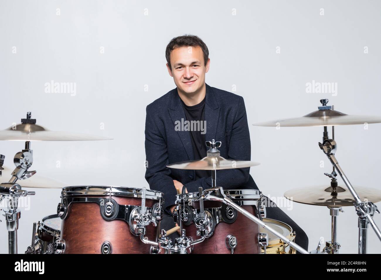Young drummer behind drum set and plays the drums in studio smiling ...