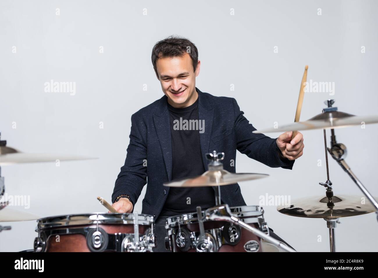 Young attractive man drummer playing drums and cymbals studio shot ...