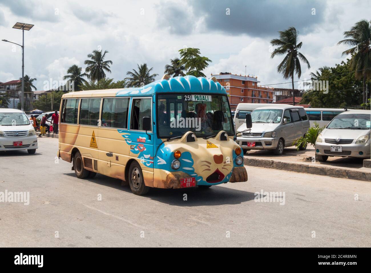 A colorful, cat-shaped bus driving by a local market in Stone Town ...