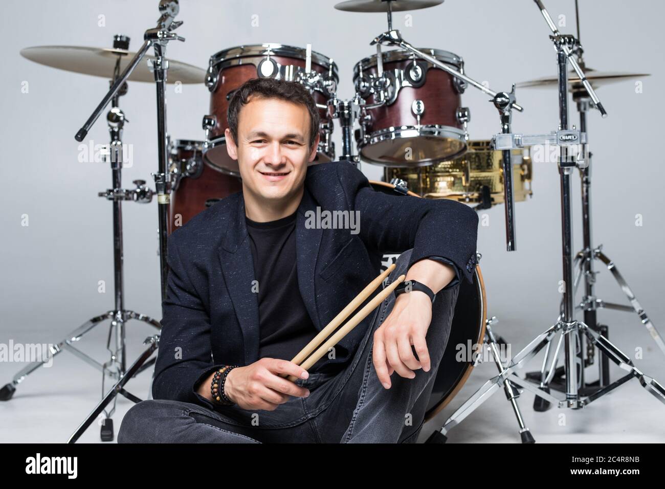 Handsome guy in front of the drum kit on a white background Stock Photo ...