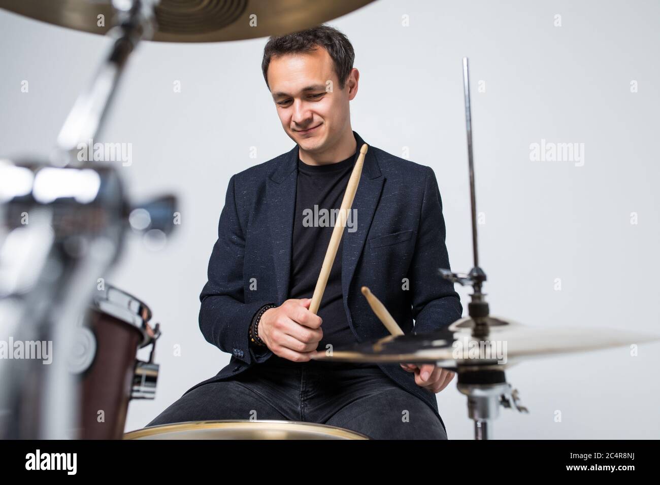 Young attractive man drummer playing drums and cymbals studio shot ...