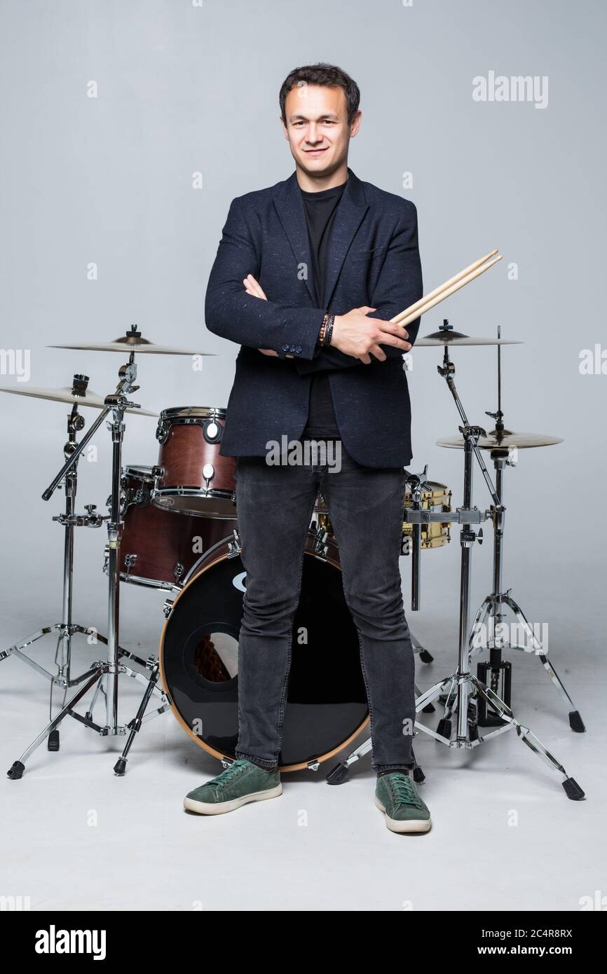 Smiling young man standing on drum set isolated on white background ...