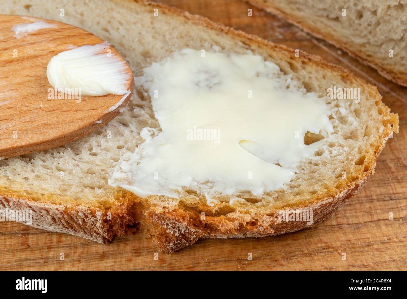 Butter spreading on fresh bread. Bread in the home kitchen. Dark ...