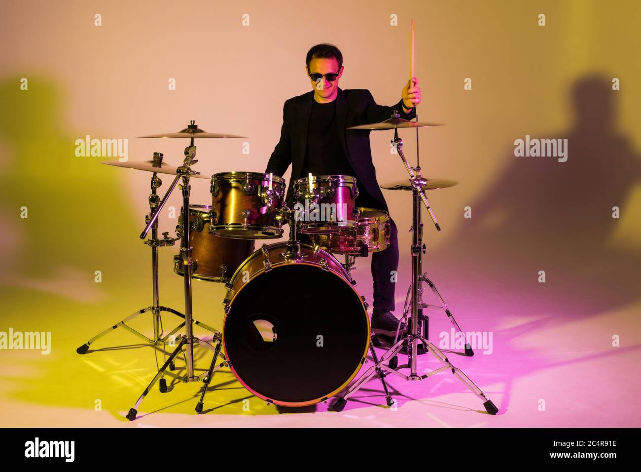 Caucasian male drummer improvising isolated on light studio background ...
