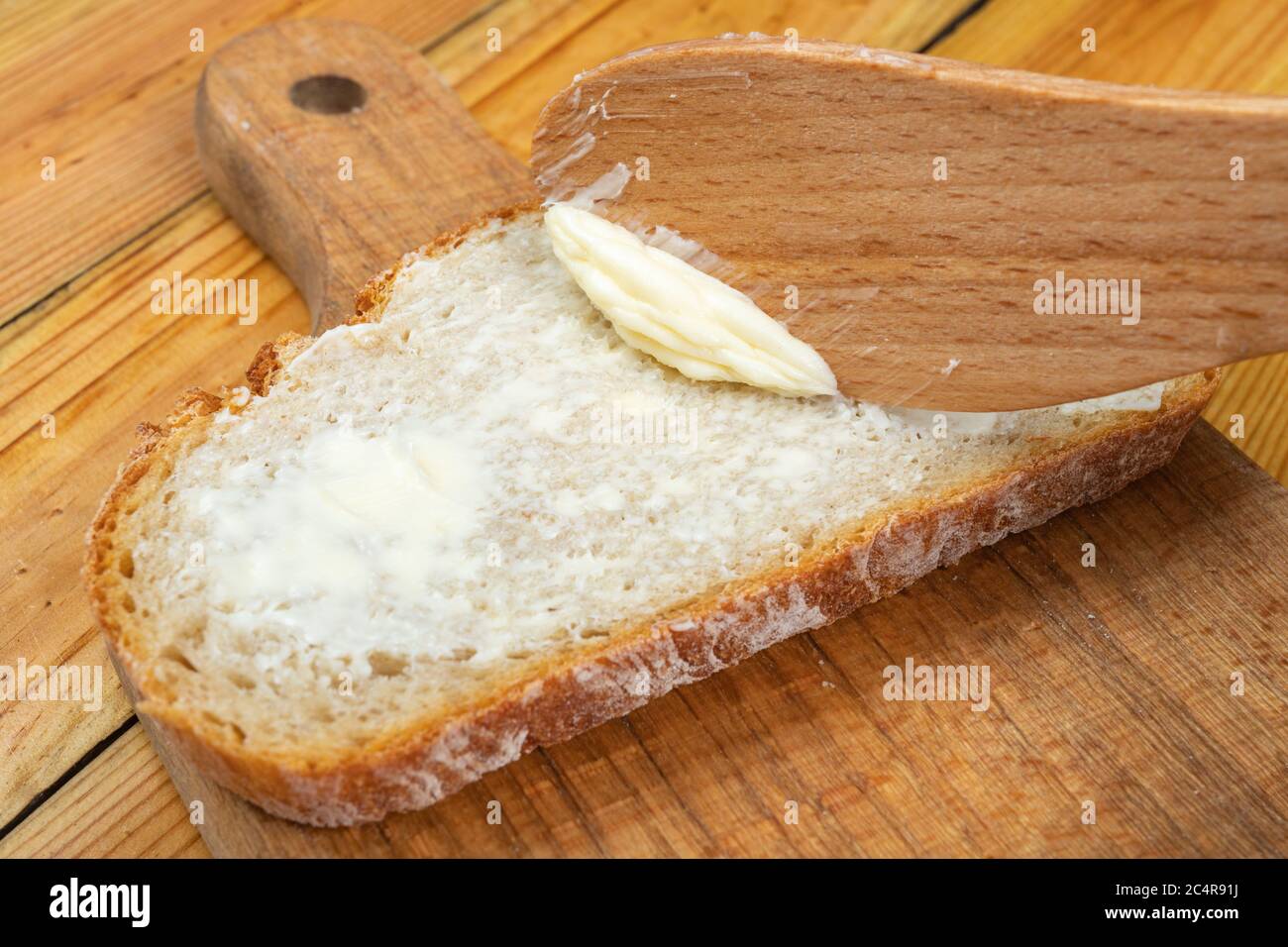 Butter spreading on fresh bread. Bread in the home kitchen. Dark ...
