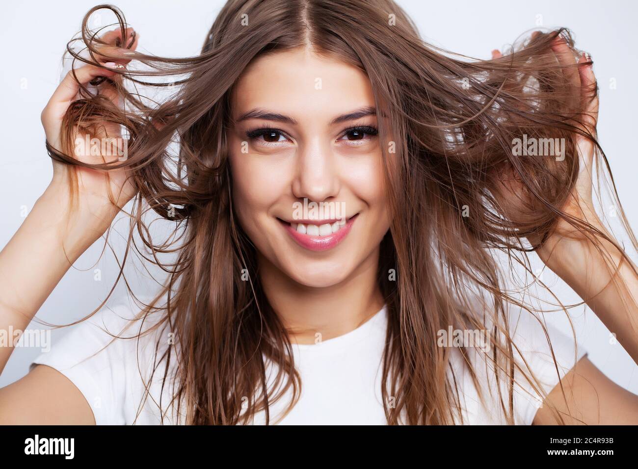 Beautiful young female model takes care of her hair and uses a hair ...