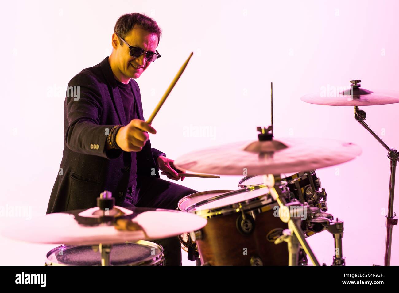 Caucasian male drummer improvising isolated on light studio background ...