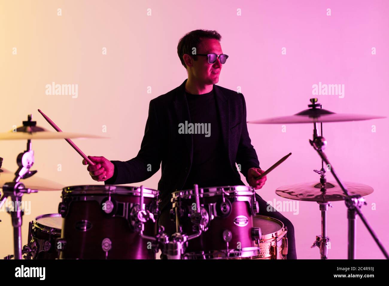 Caucasian male drummer improvising isolated on light studio background ...