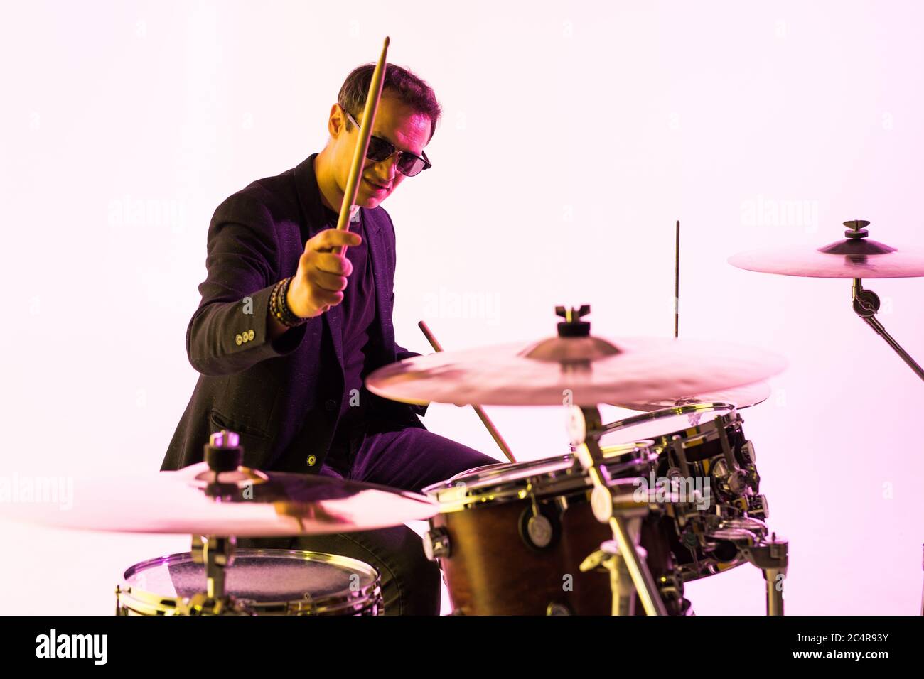 Caucasian male drummer improvising isolated on light studio background ...