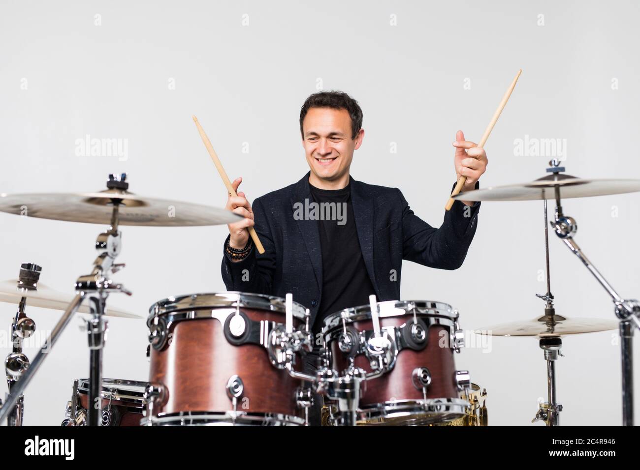 Young handsome man play with drumsticks sitting at drums isolated on ...