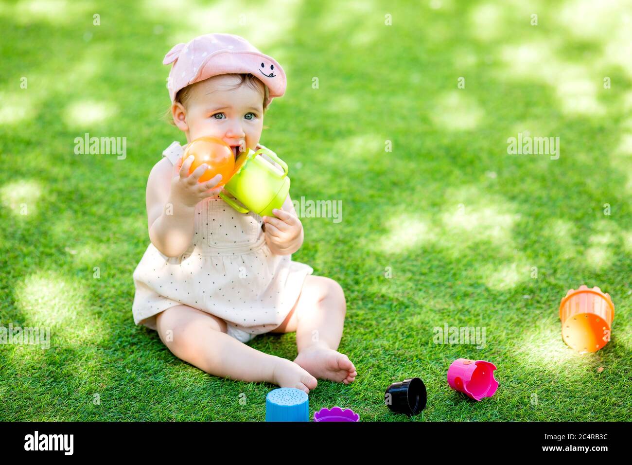 Toddler girl sits in summer on green lawn playing in a pyramid scheme ...
