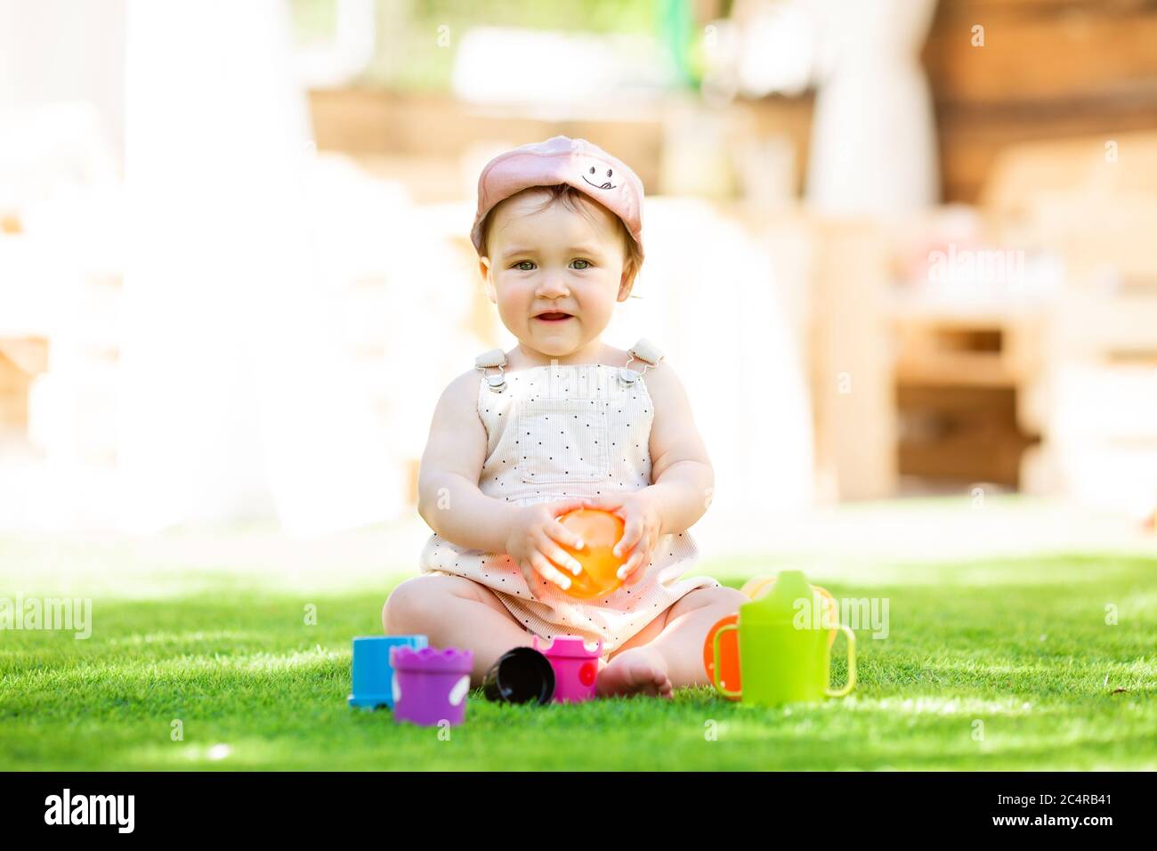 Toddler girl sits in summer on green lawn playing in a pyramid scheme ...