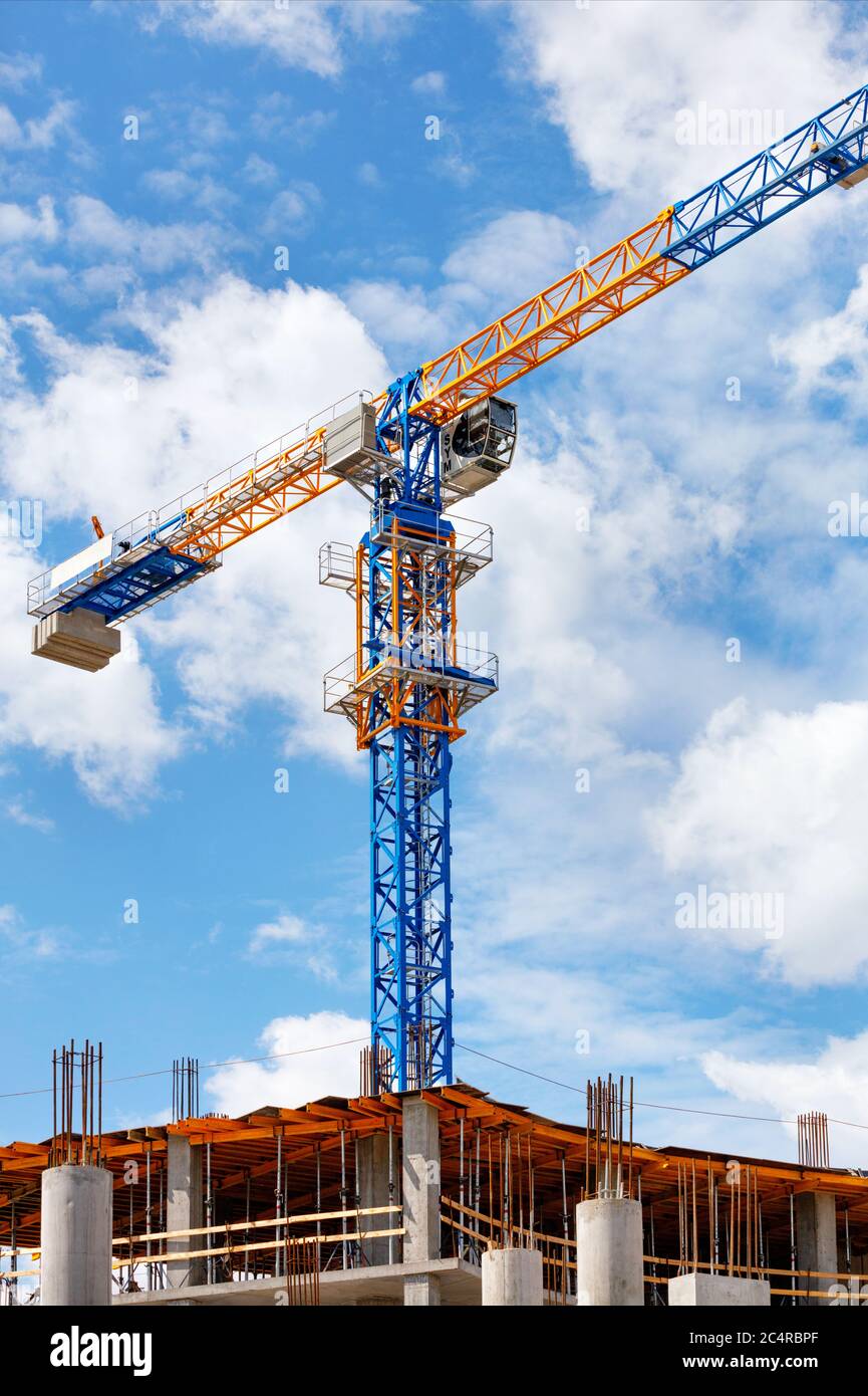 The arrow of a yellow and blue high-rise tower crane rises above the ...