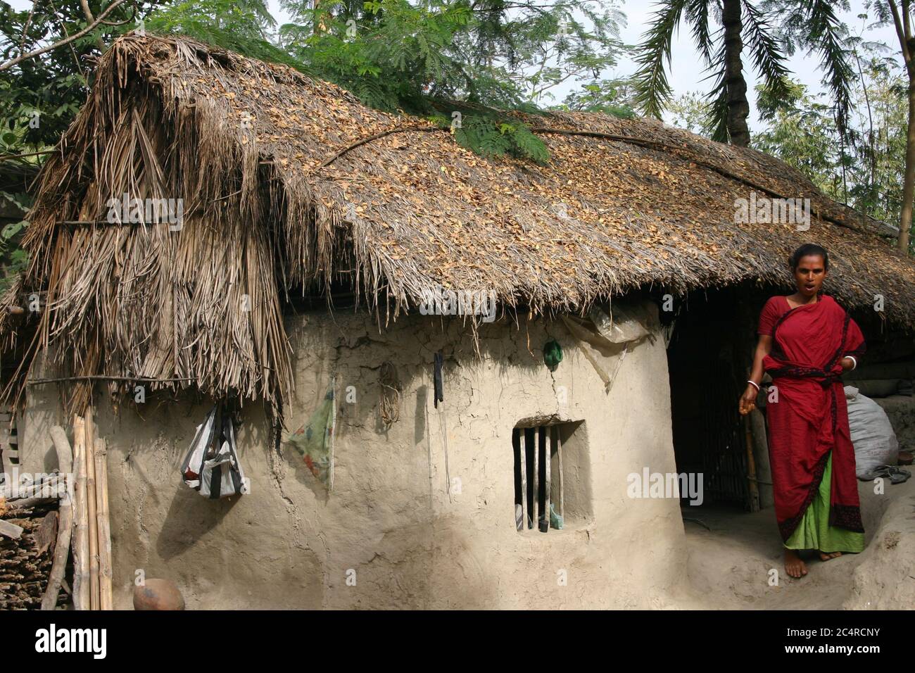 A rural woman stands in front of her mud house. Khulna, Bangladesh ...