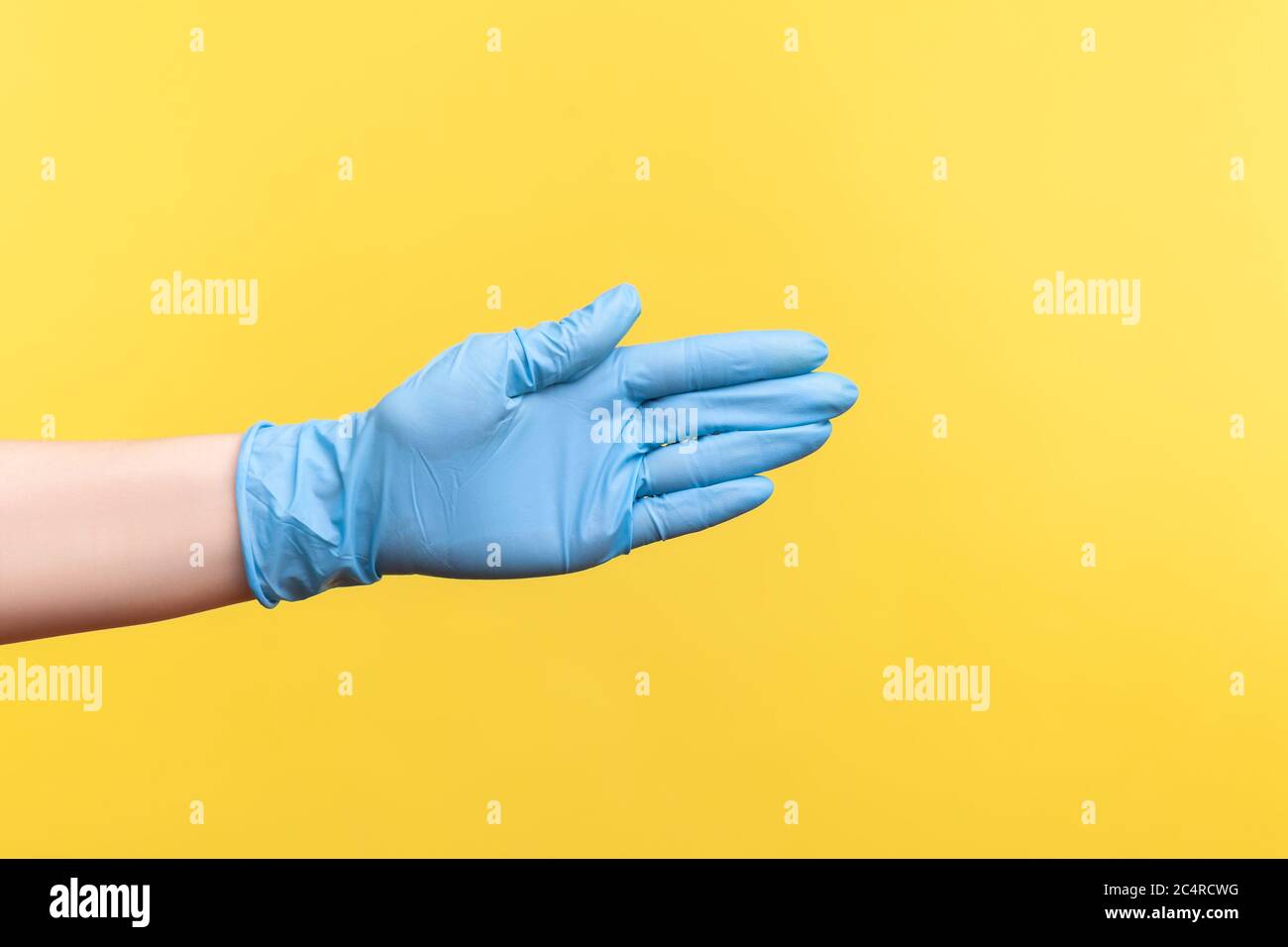 Profile side view closeup of human hand in blue surgical gloves giving ...
