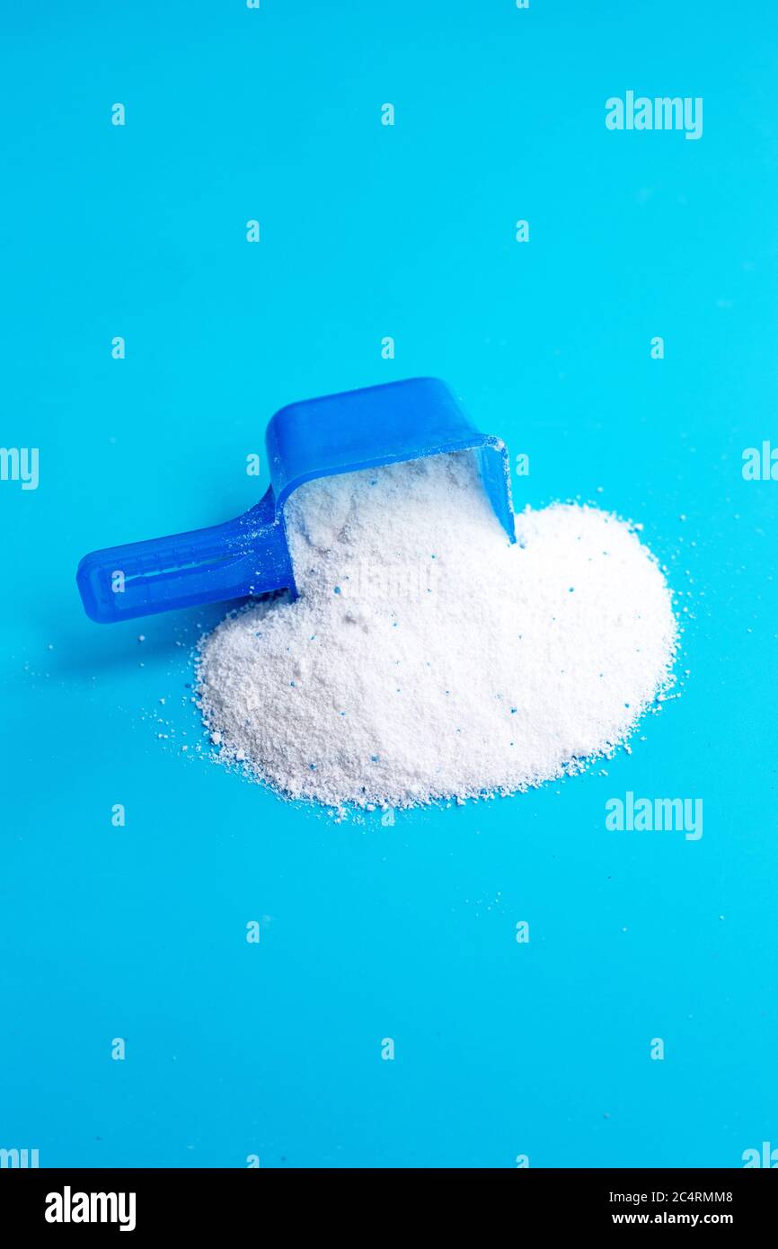Detergent powder with measuring spoon for clothes washing on blue ...