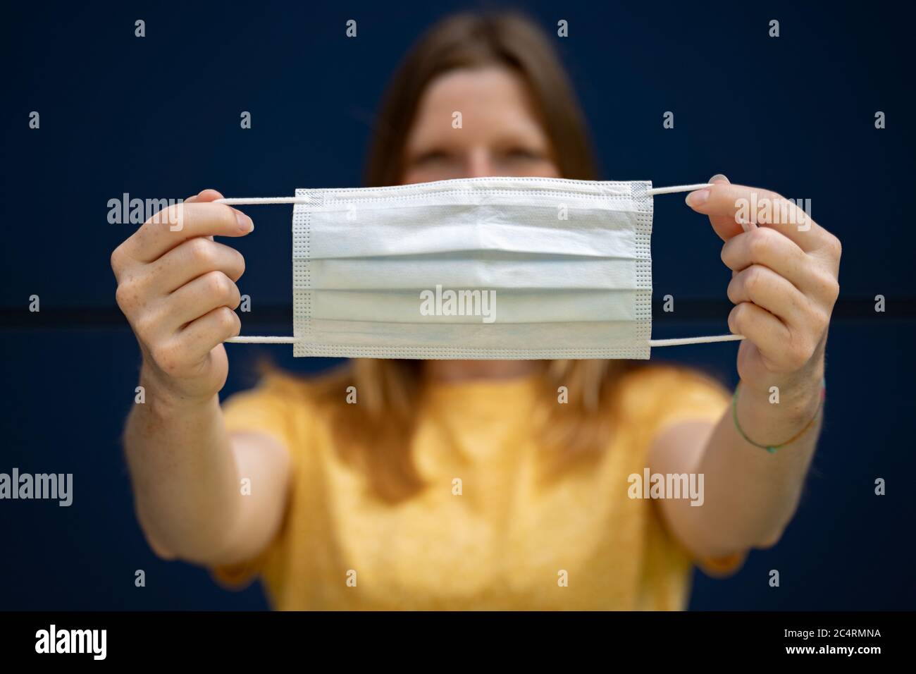 Woman holding disposable surgical face mask in outstretched hands in ...