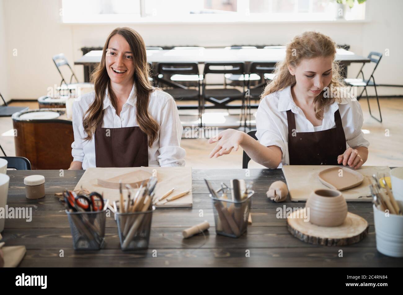 Women working In pottery studio, smiling and talking. Ceramic workshop ...