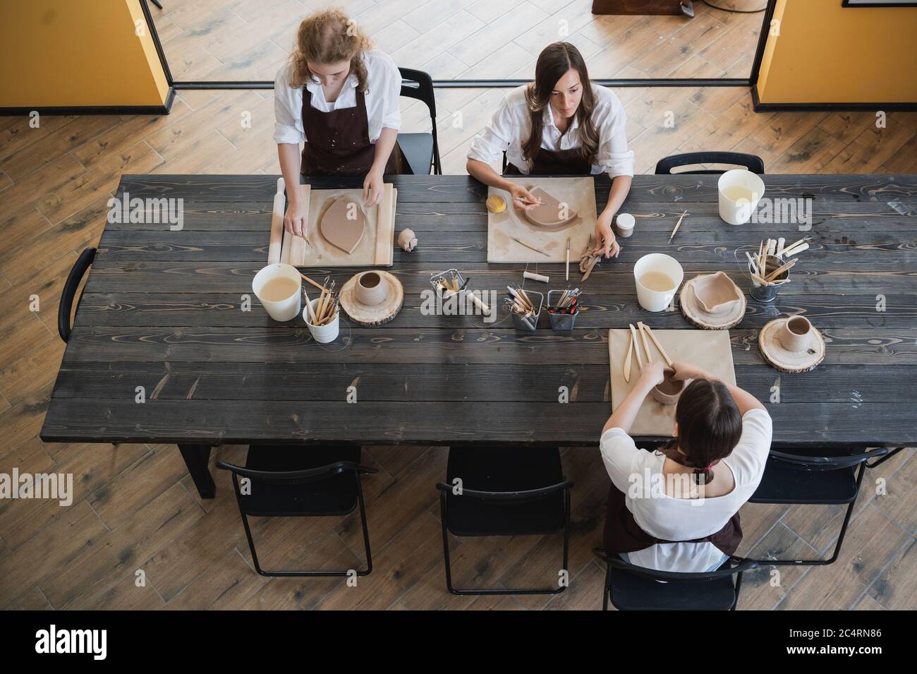 Top view of female artists sculpting different clay products on a big ...