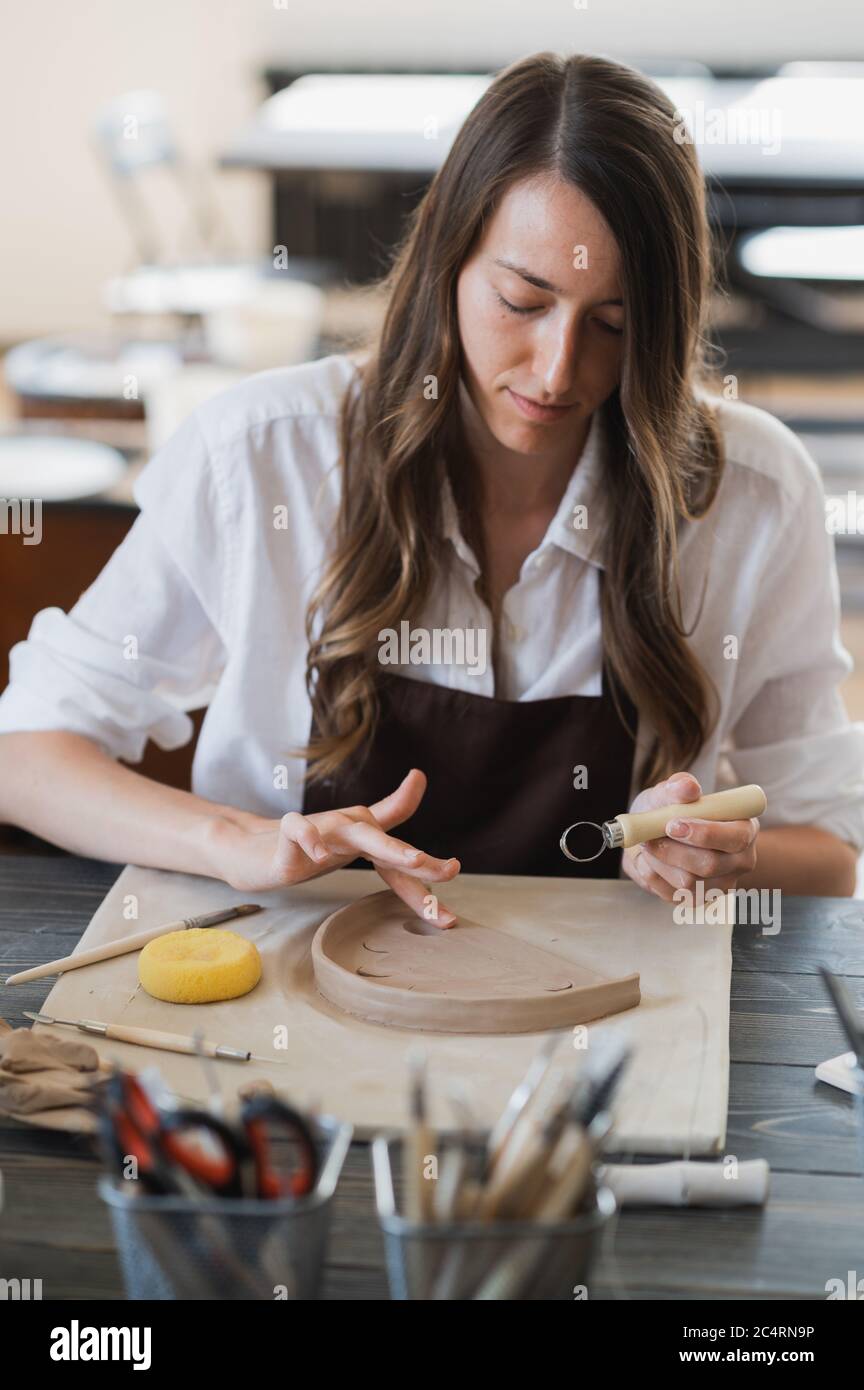 Close-up of a master potter, clay cutting special tool. Female artist ...