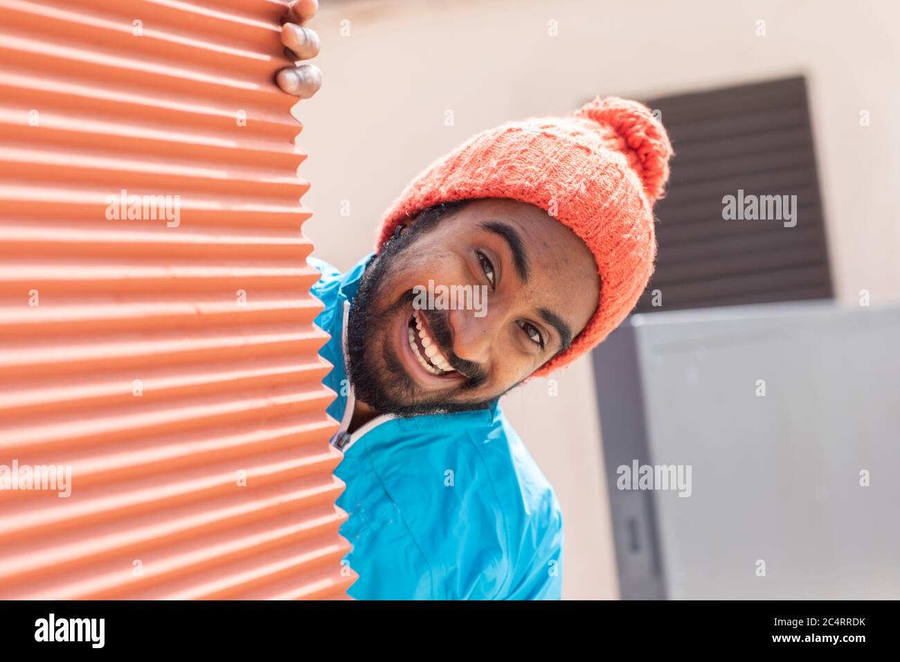 face of a young man behind a wall with red cap Stock Photo - Alamy