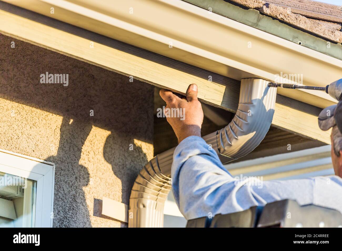 Worker Attaching Aluminum Rain Gutter and Down Spout to Fascia of House ...