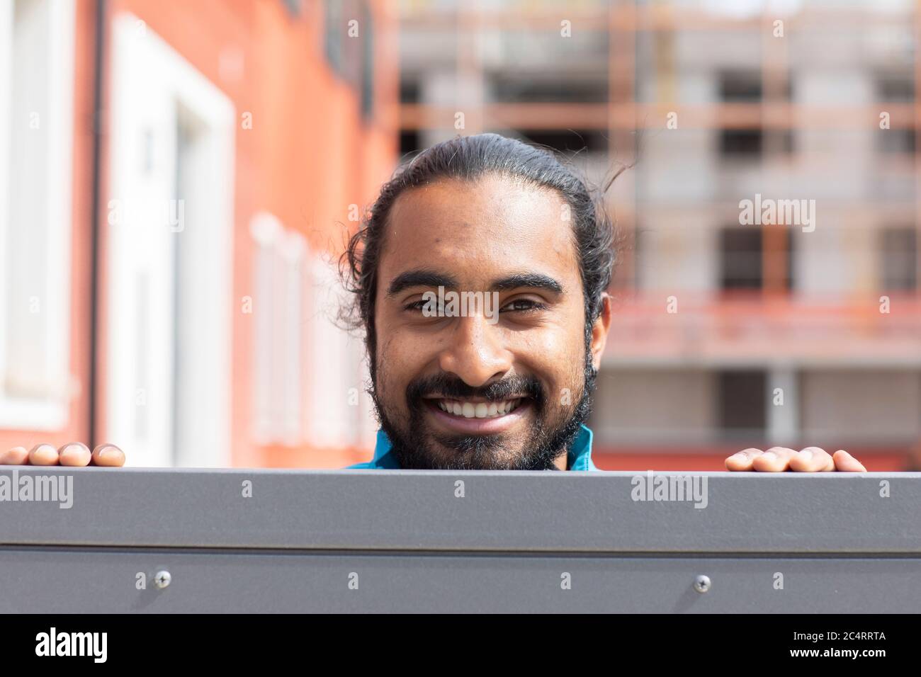 young man smiling behind a wall Stock Photo - Alamy