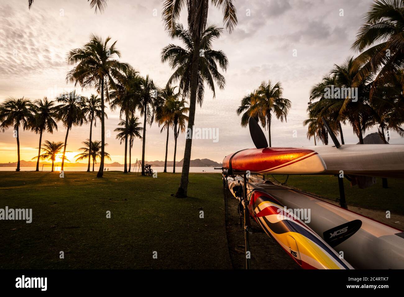 Beautiful view to the sun rising with palm trees and sport canoes ...