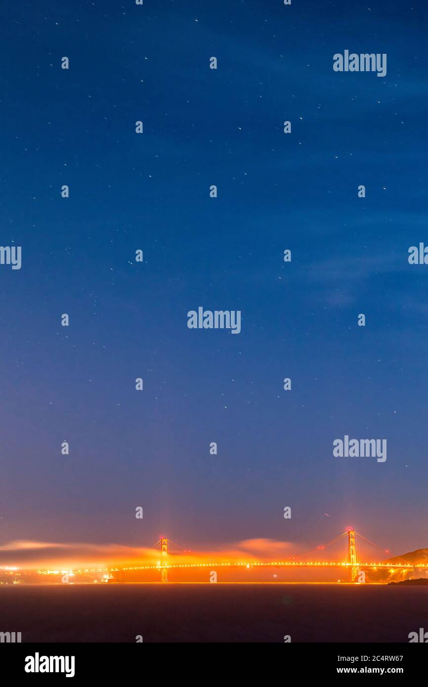 The Golden Gate Bridge with clouds and stars at night. Viewed from ...