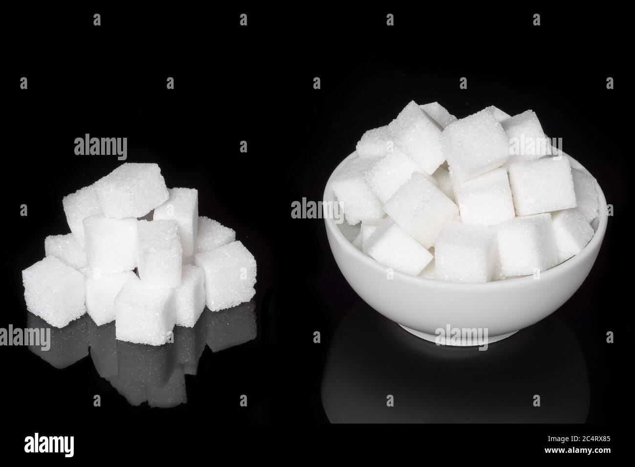 Cube sugar, sugar cubes in a round dish, and stacked against a black ...