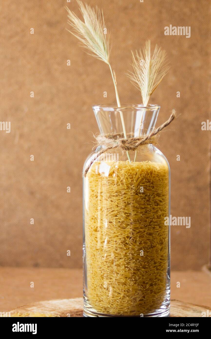 Small vermicelli in a glass jar on a wooden stand, scattered on the ...
