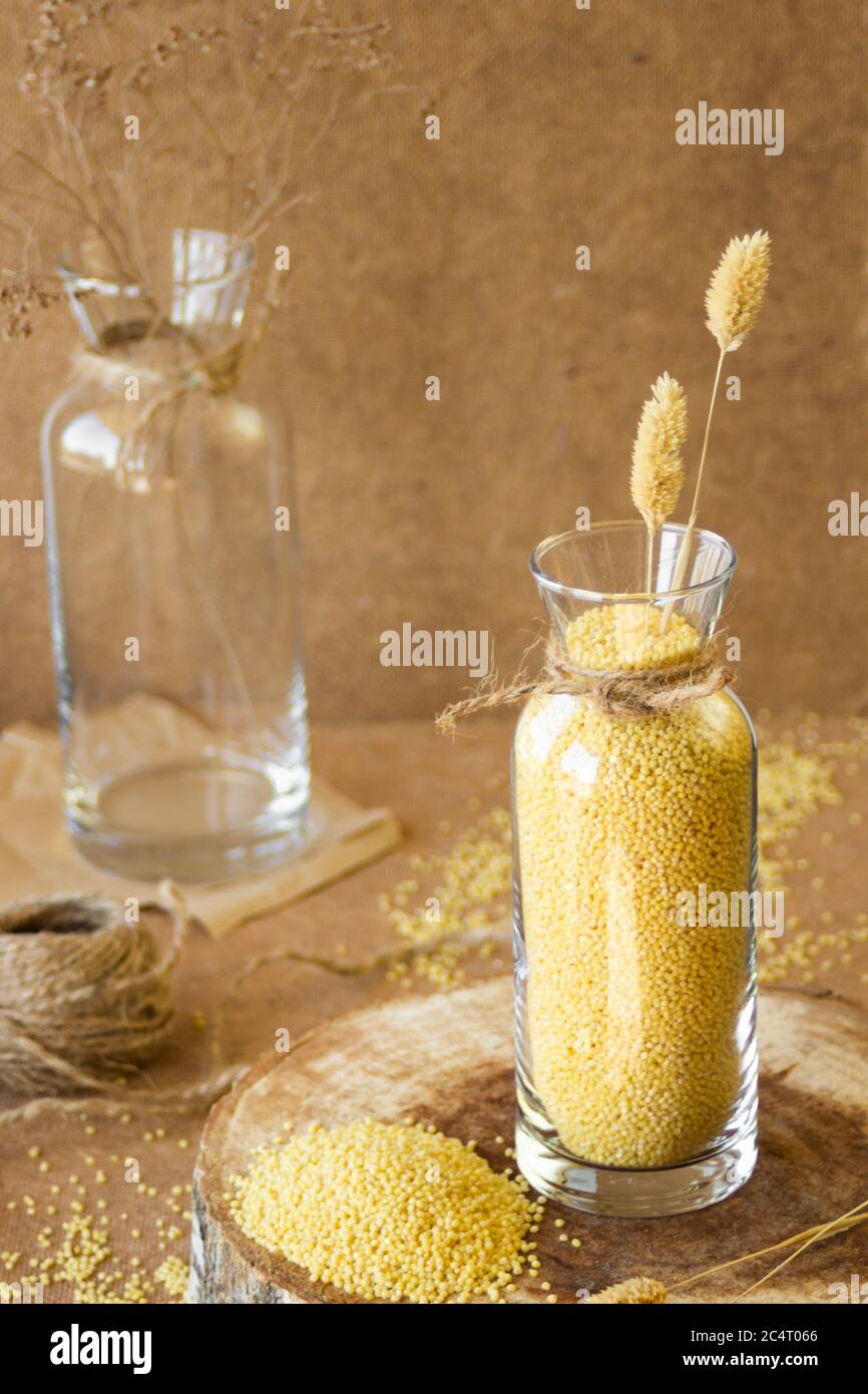 Millet in a glass jar on a wooden stand, next is an ear of wheat Stock ...