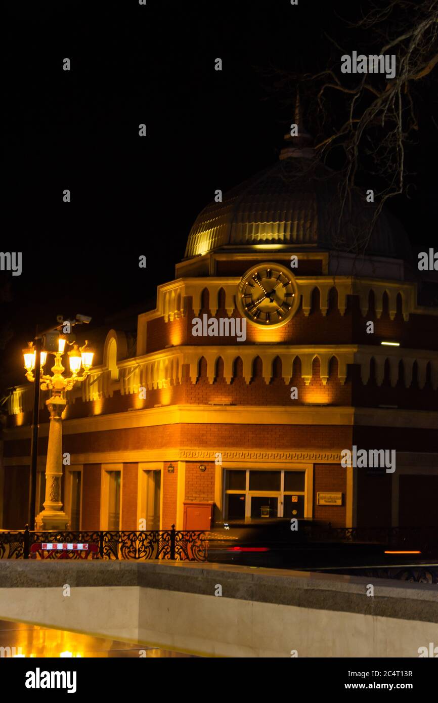 Winter night city with blue and yellow lights and fountains in the park ...