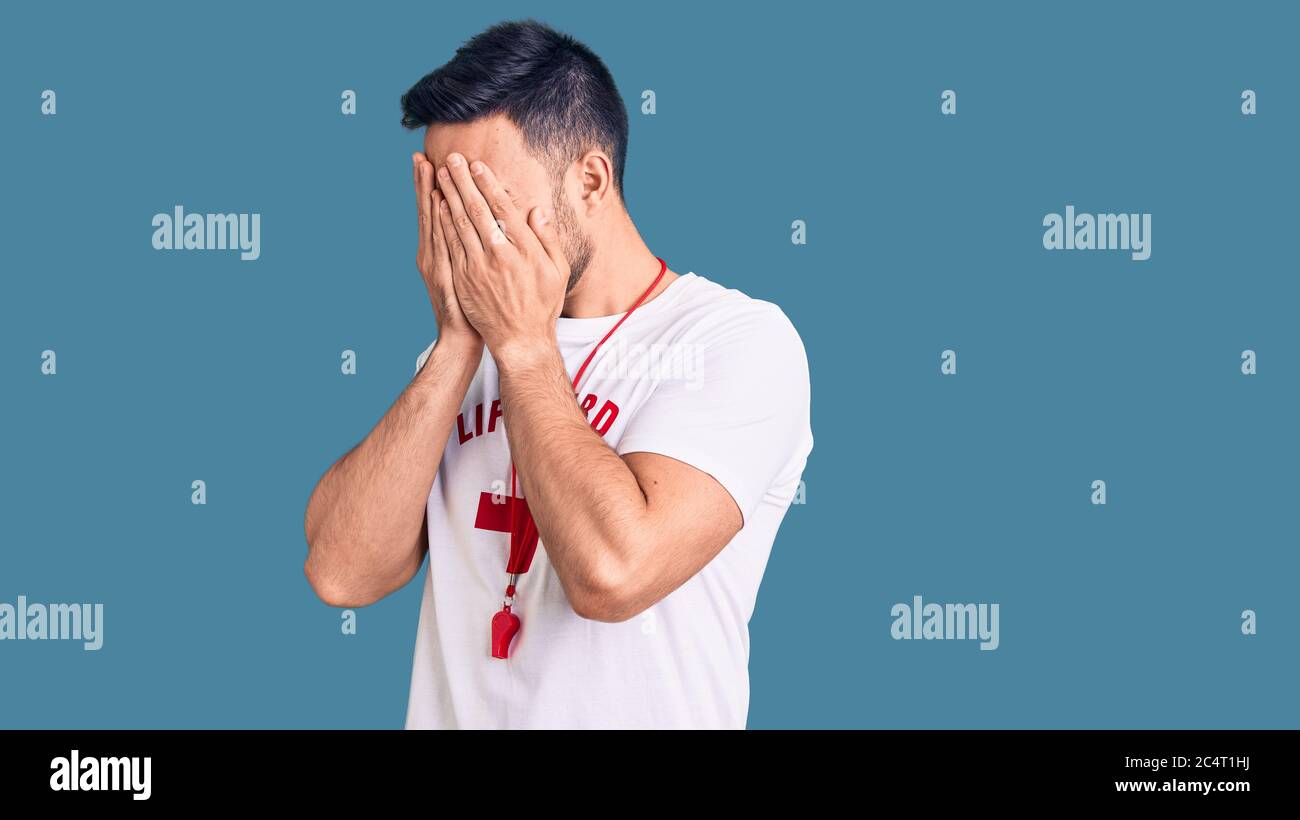 Young handsome man wearing lifeguard uniform with sad expression ...
