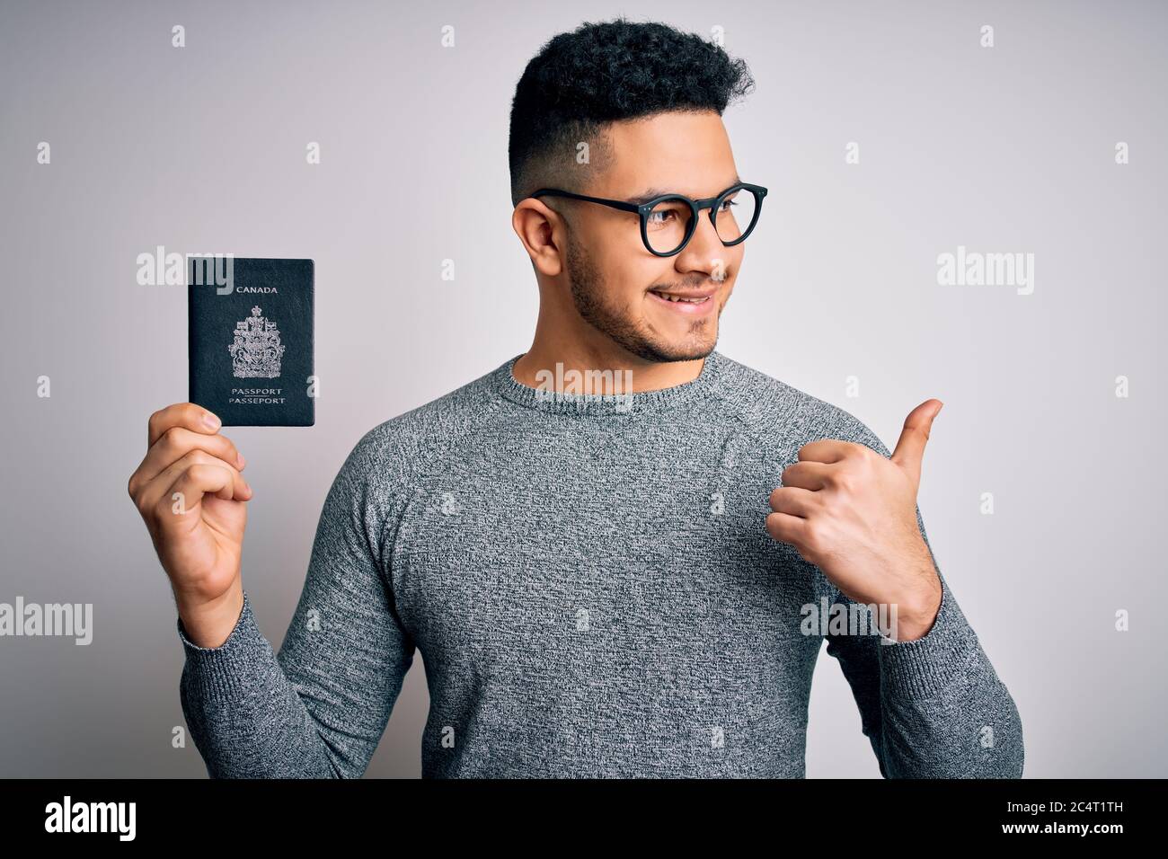 Young handsome tourist man on vacation wearing glasses holding Canada ...
