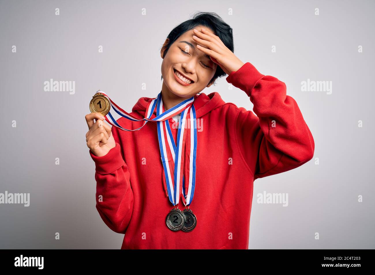 Young beautiful asian girl winner wearing medals over isolated white ...