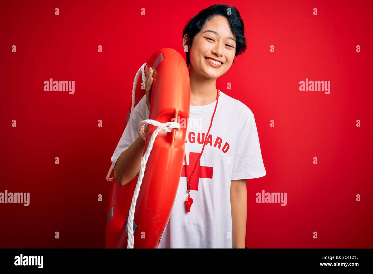 Young beautiful asian lifeguard girl using whistle holding orange float ...