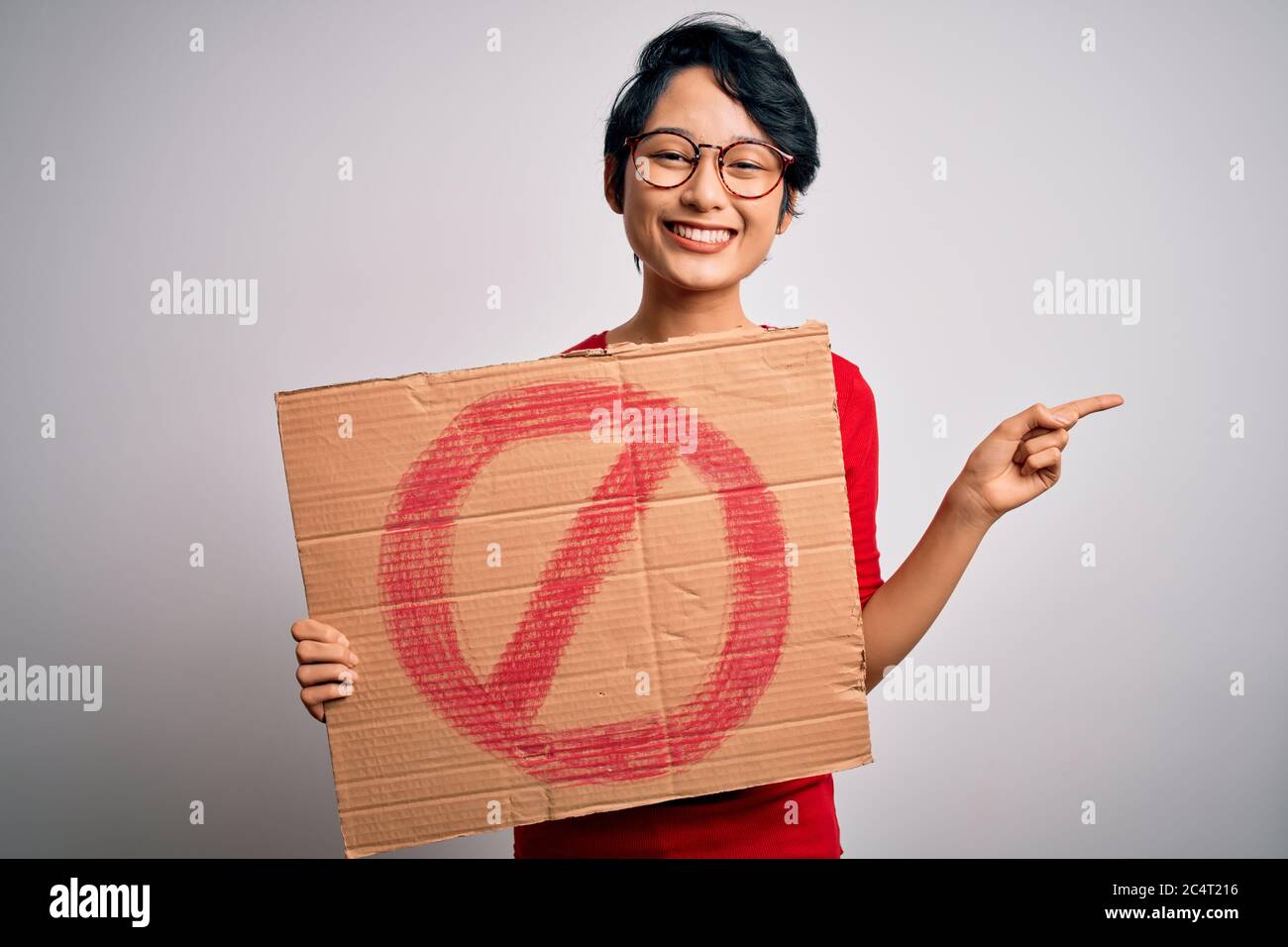 Young beautiful asian girl holding banner with prohibited signal over ...
