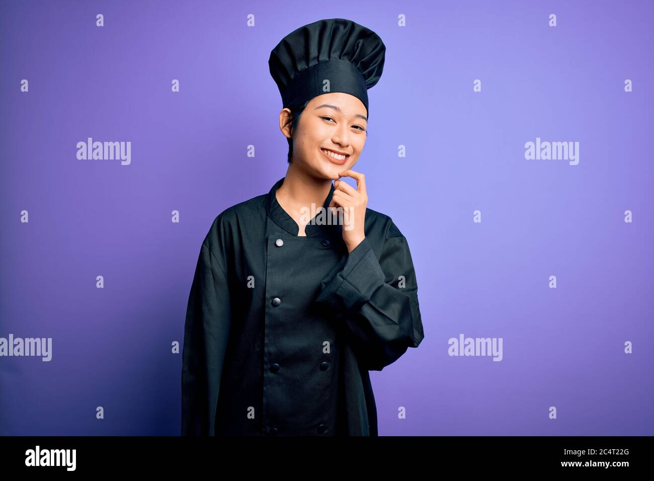 Young beautiful chinese chef woman wearing cooker uniform and hat over ...