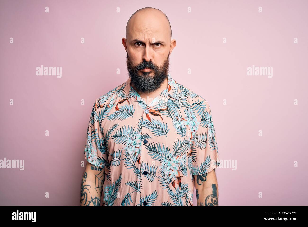 Handsome bald man with beard and tattoo wearing casual floral shirt ...