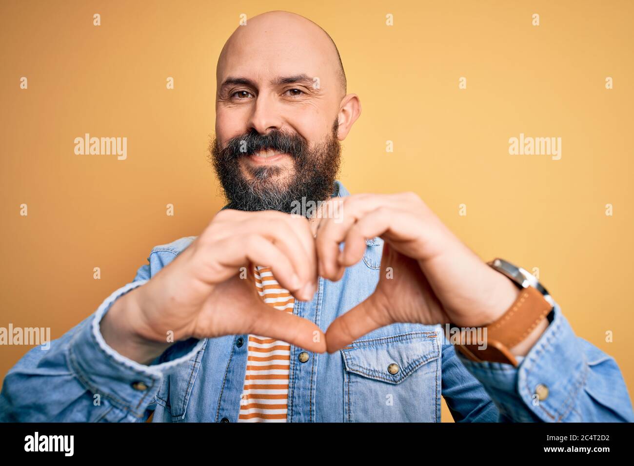 Handsome bald man with beard wearing casual denim jacket and striped t ...