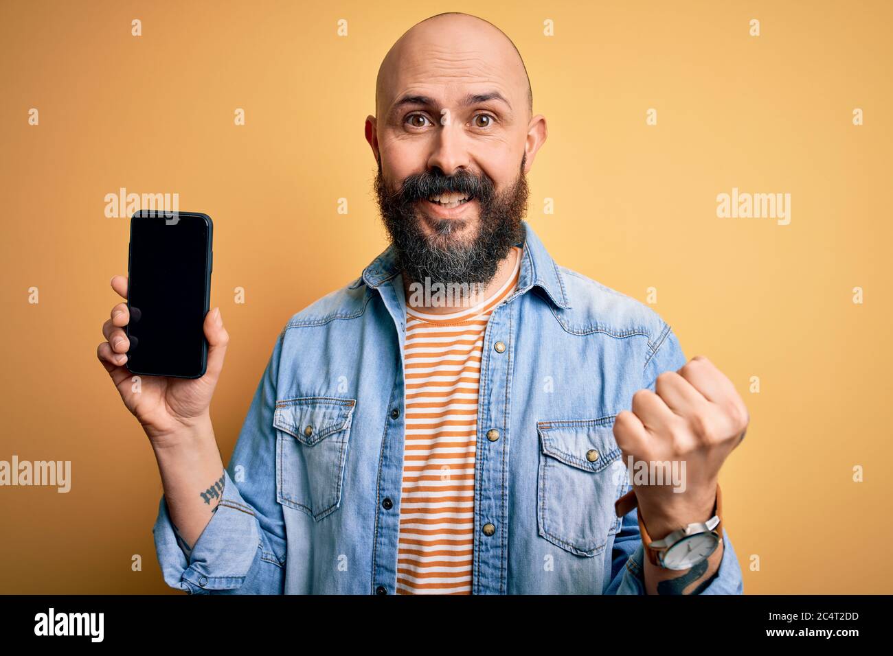 Handsome bald man with beard holding smartphone showing screen over ...
