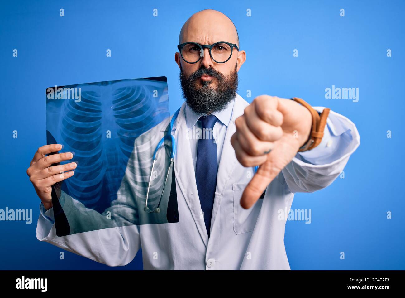 Handsome bald doctor man with beard wearing stethoscope holding chest ...