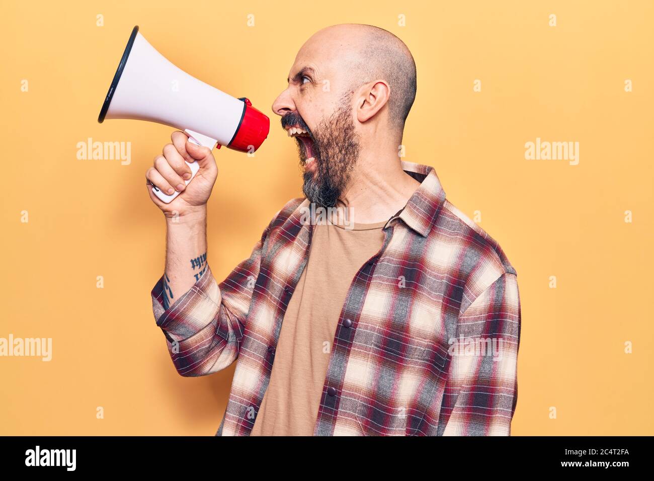 Young handsome bald man with angry expression. Screaming loud using ...