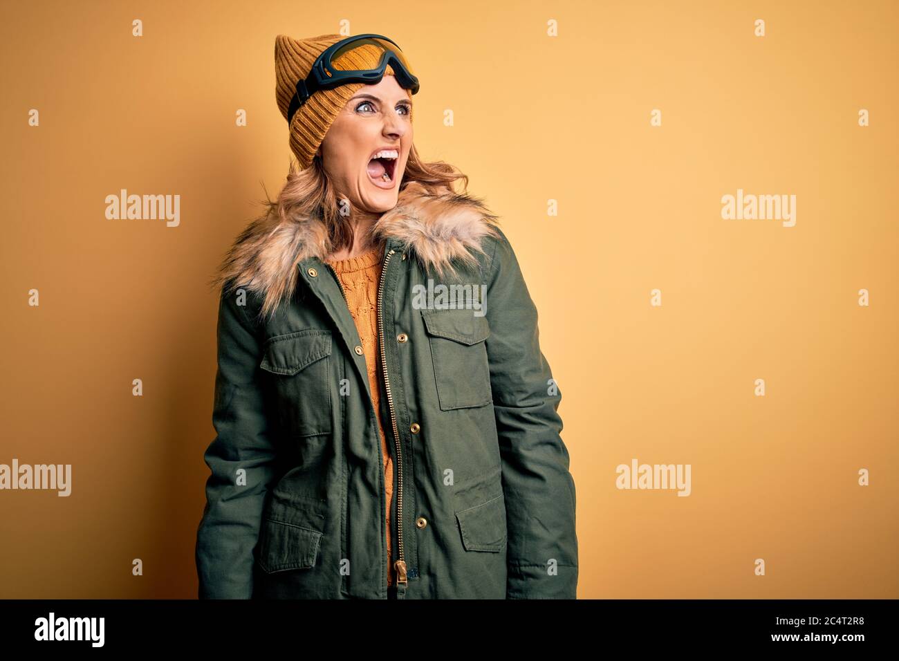 Middle age beautiful blonde skier woman wearing snow sportwear and ski ...