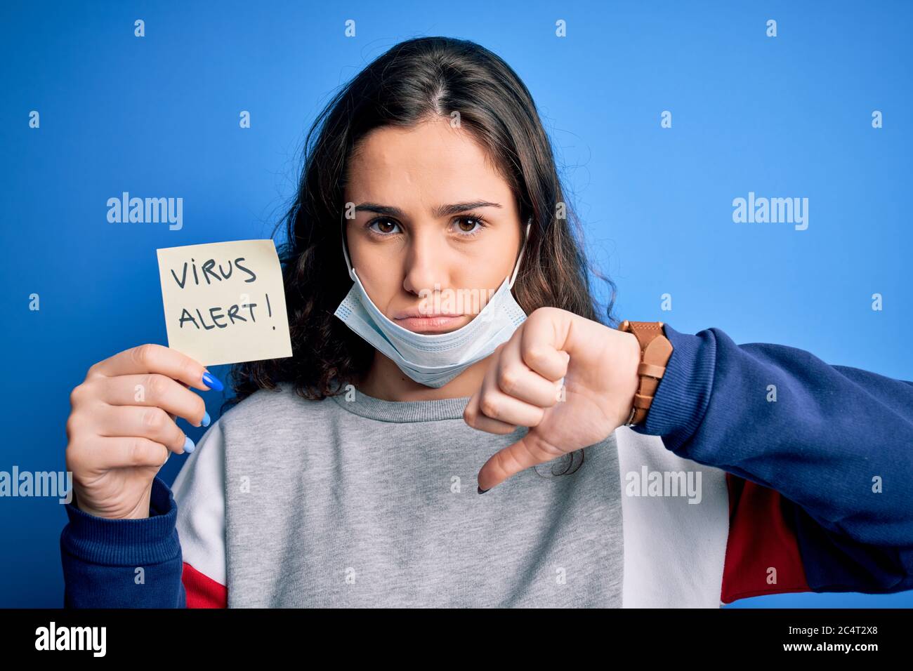 Young beautiful woman with curly hair wearing mask holding reminder ...