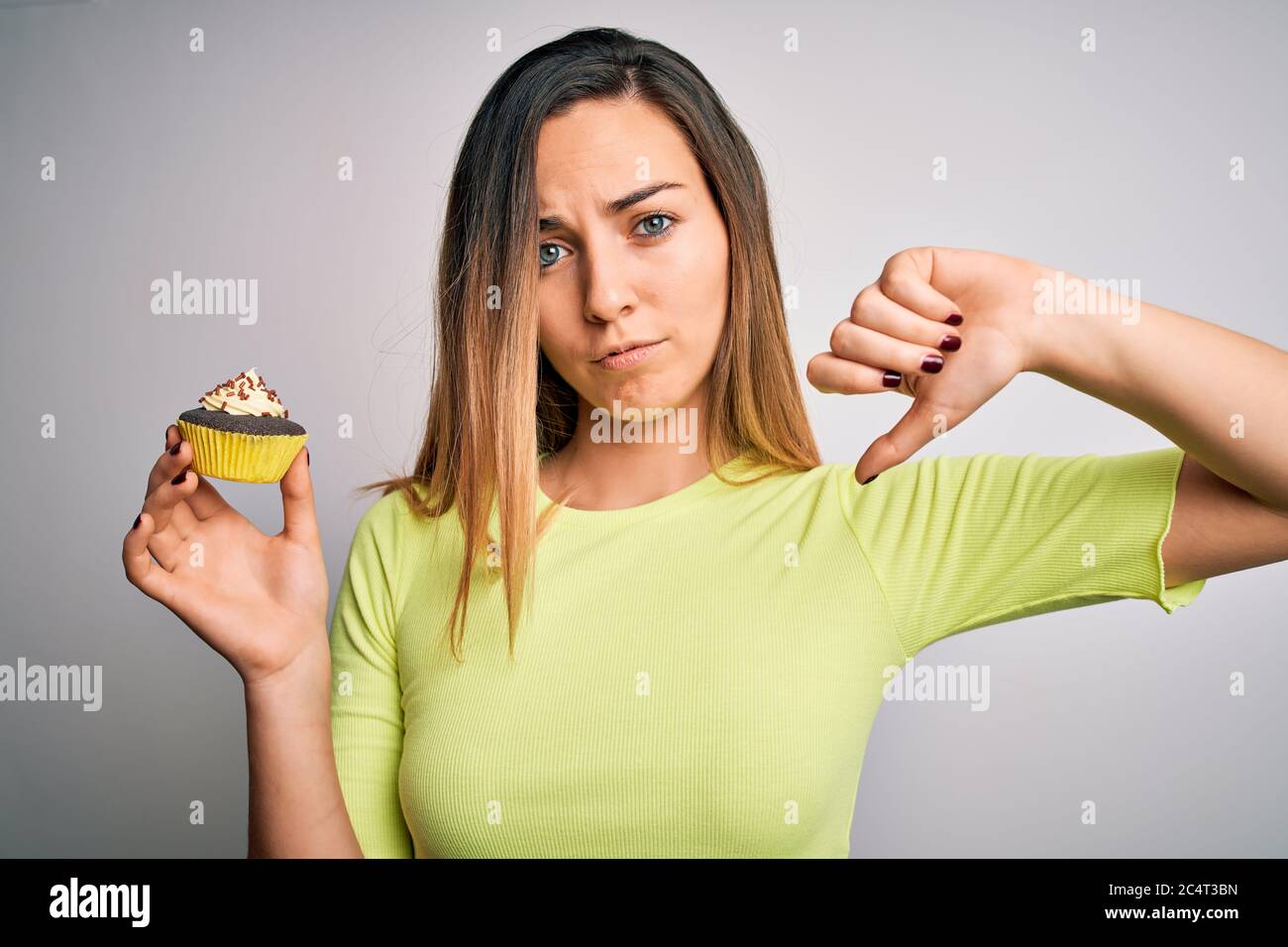 Young beautiful woman with blue eyes eating sweet chocolate cupcake ...
