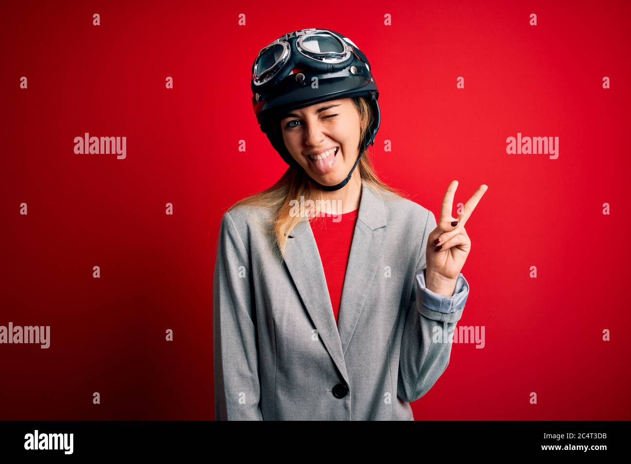 Young beautiful blonde motorcyclist woman wearing motorcycle helmet ...