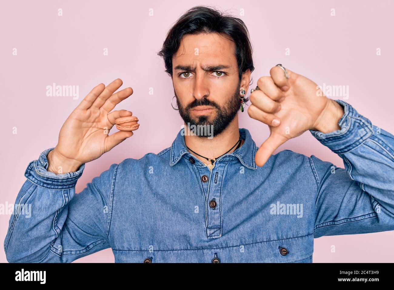 Young handsome hispanic bohemian hipster man with bear holding sweet ...